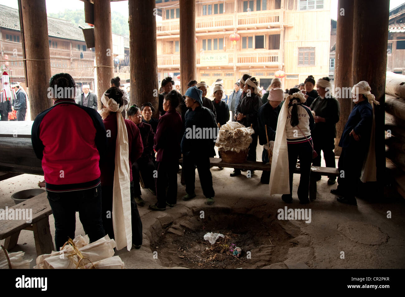 A small crowd with white scarves at a funeral rite under a Drum Tower ...