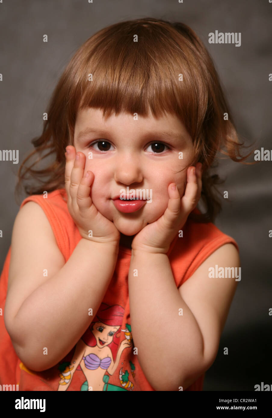 Portrait of the two-year-old girl which behaves hands for the face ...