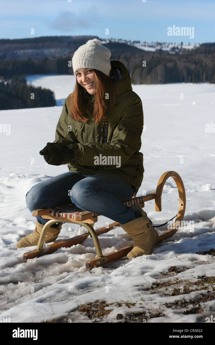 Young woman sitting on a sled, sledging, Black Forest, Baden ...