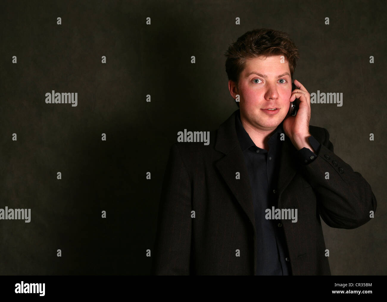 Businessman making a phone call on a dark background Stock Photo - Alamy