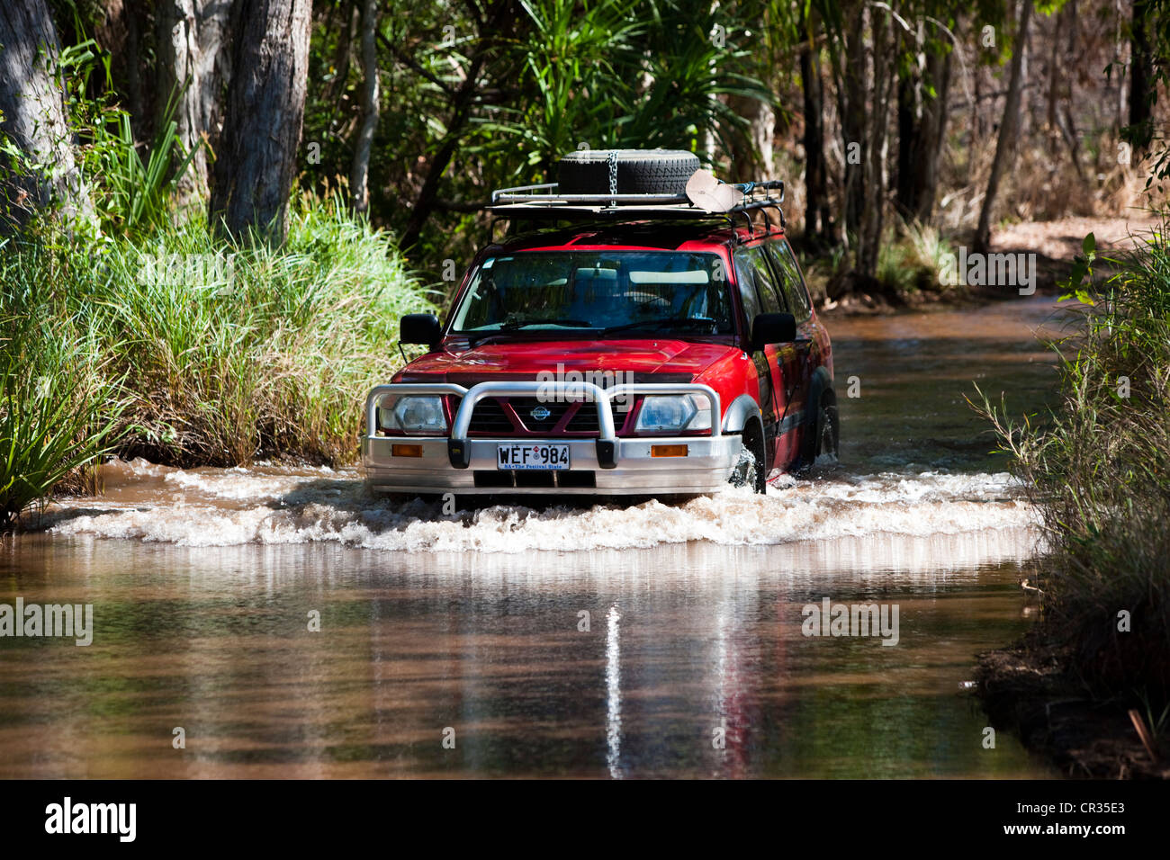 Four-wheel vehicle crossing a river in Litchfield National Park ...