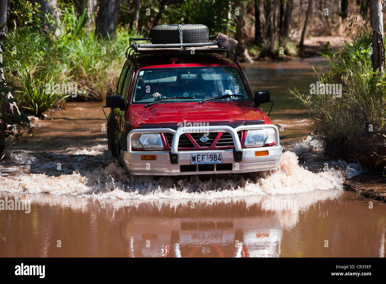 Four-wheel vehicle crossing a river in Litchfield National Park ...