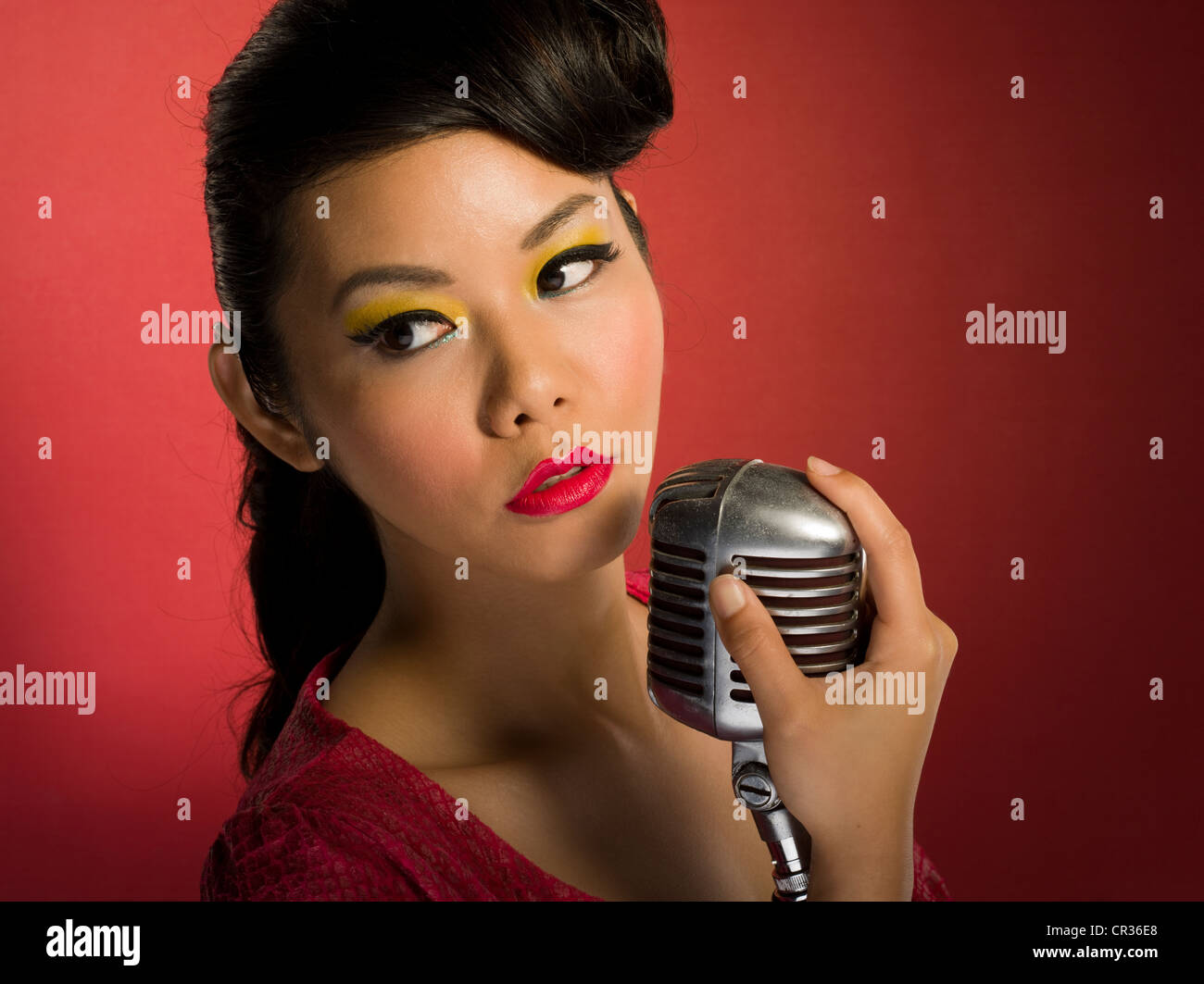 Asian woman singing into microphone Stock Photo - Alamy