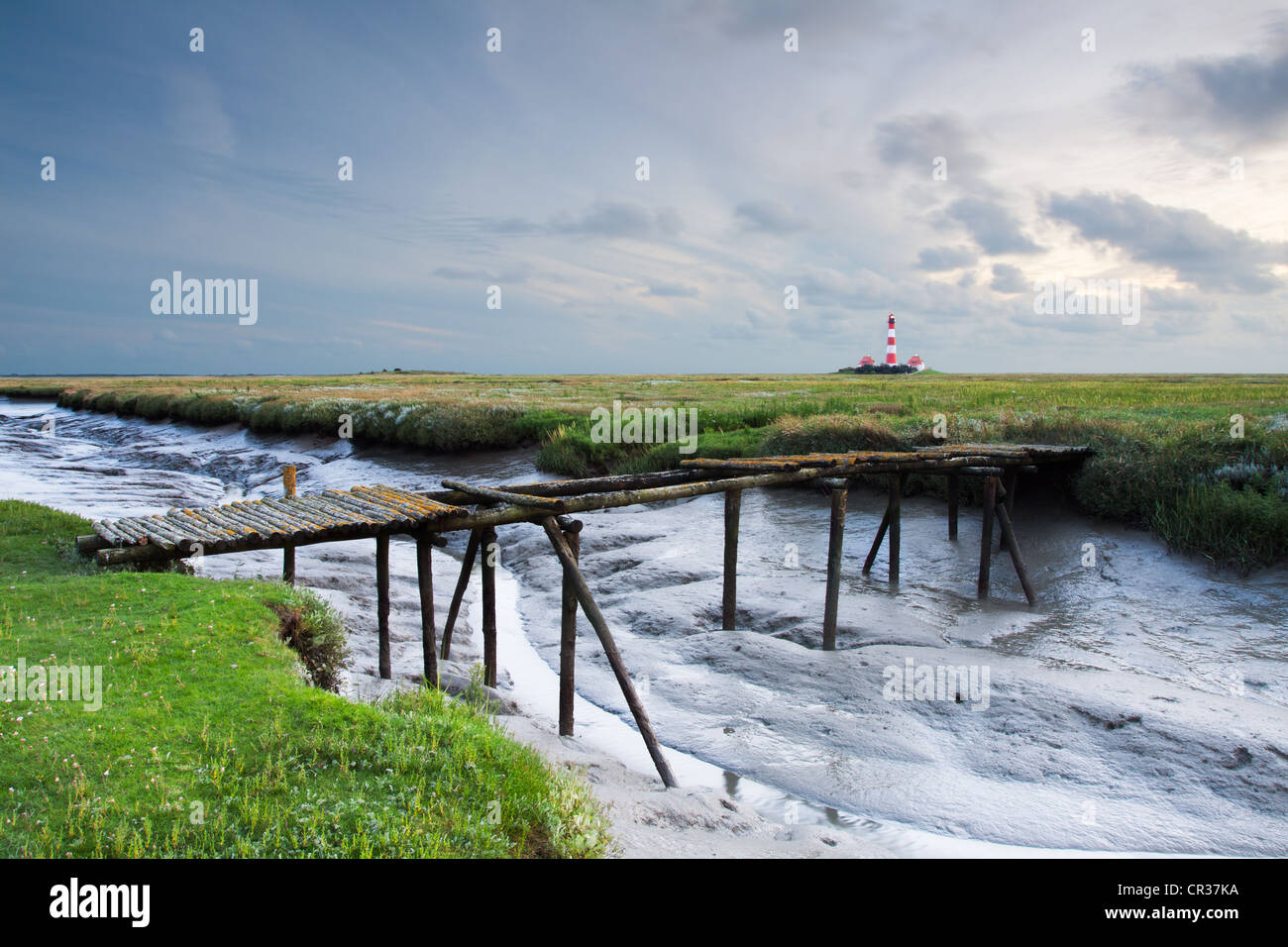 Westerhever lighthouse with a dilapidated bridge over a tidal gully ...