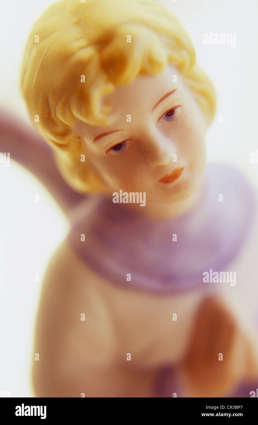 Close up of face and head of painted porcelain young angel with golden ...