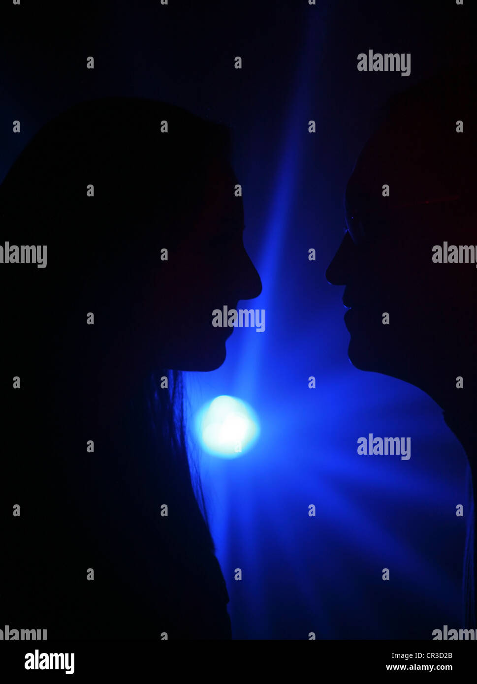 Two people in silhouette on a dark blue background Stock Photo - Alamy