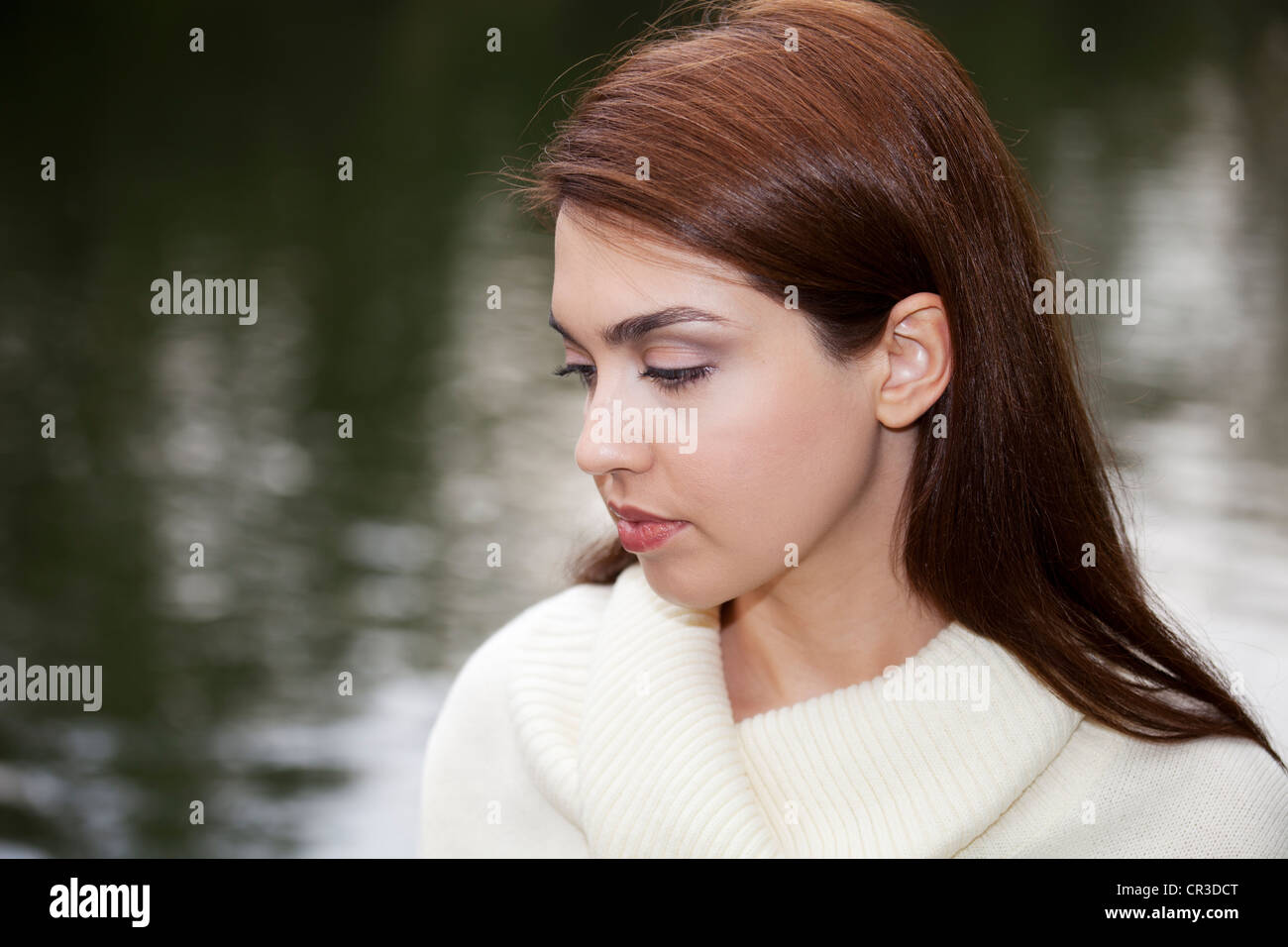 Young woman looking thoughtful, lowered eyes, in front of a lake Stock ...