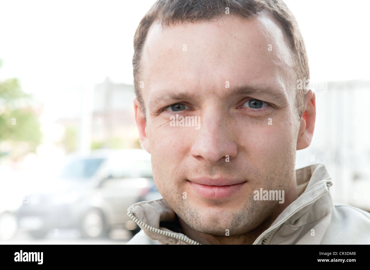Closeup portrait of young slightly smiling Caucasian man in the city ...