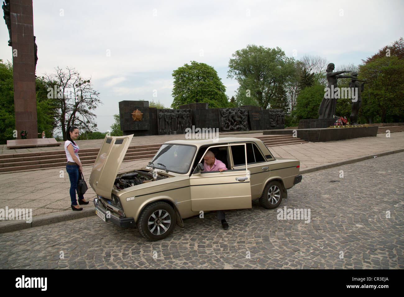 A young man repairing his Lada, his girlfriend standing on the left ...