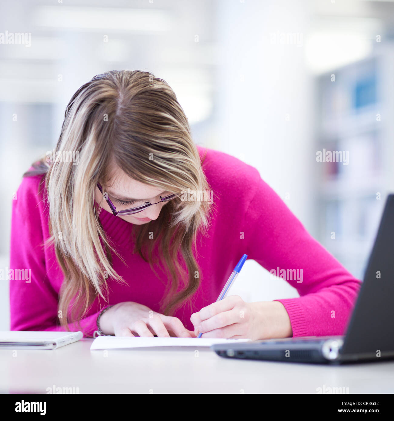 in the library - pretty, female student with laptop and books working ...