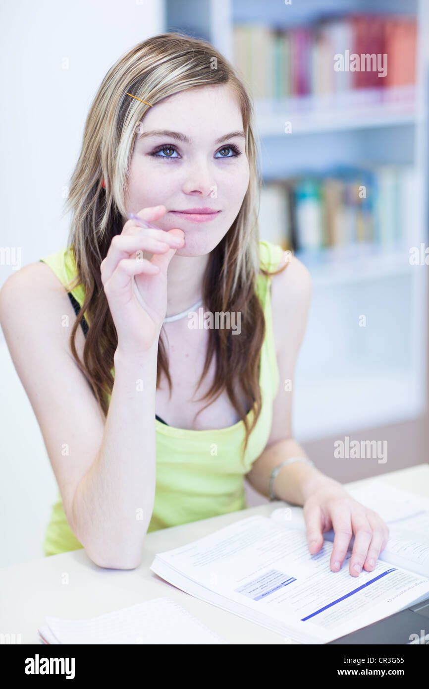 in the library - pretty, female student with laptop and books working ...