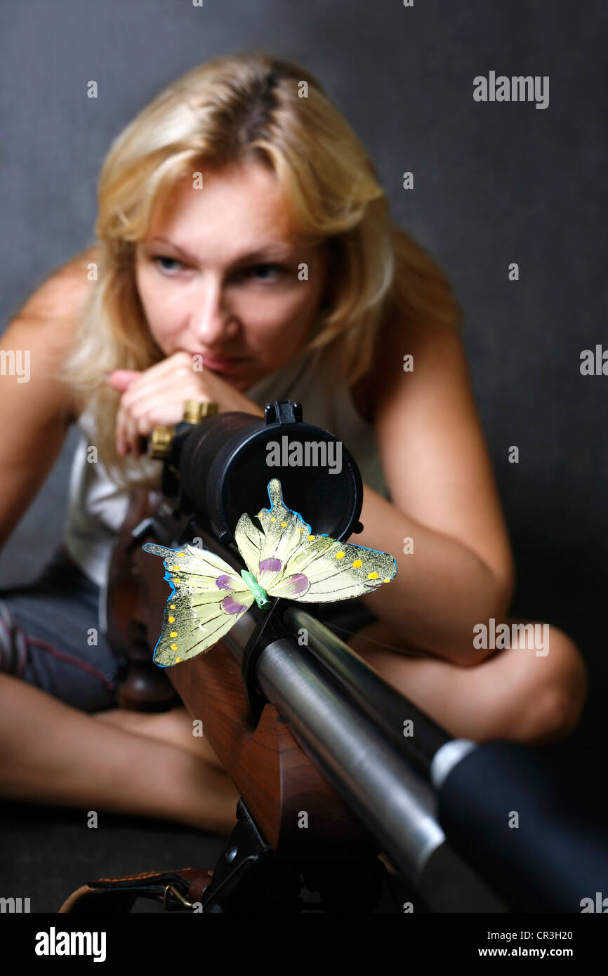 The sad girl with a gun in studio. The butterfly in a zone of focus ...