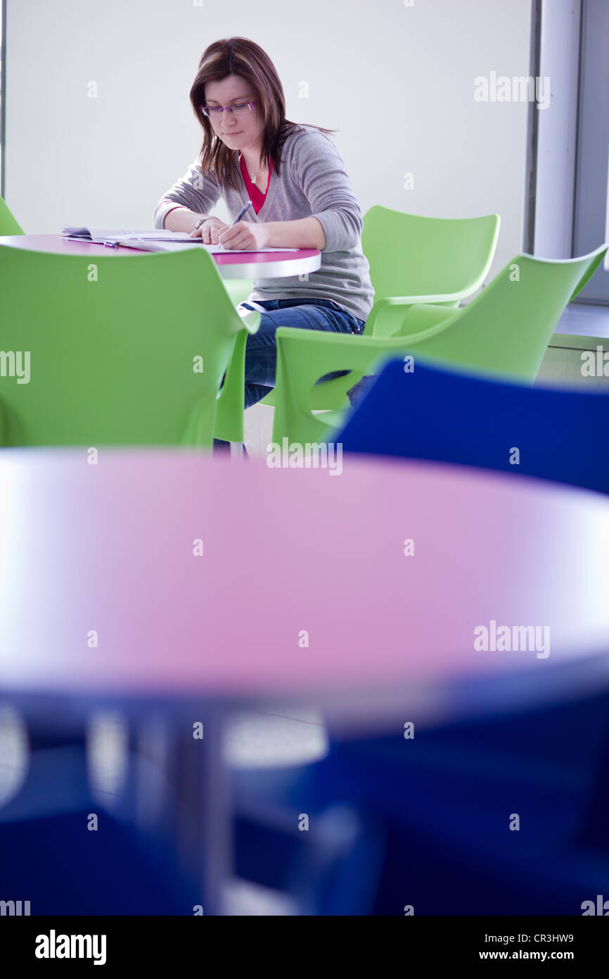 pfemale college student doing homework/assignment on campus/at scchool ...