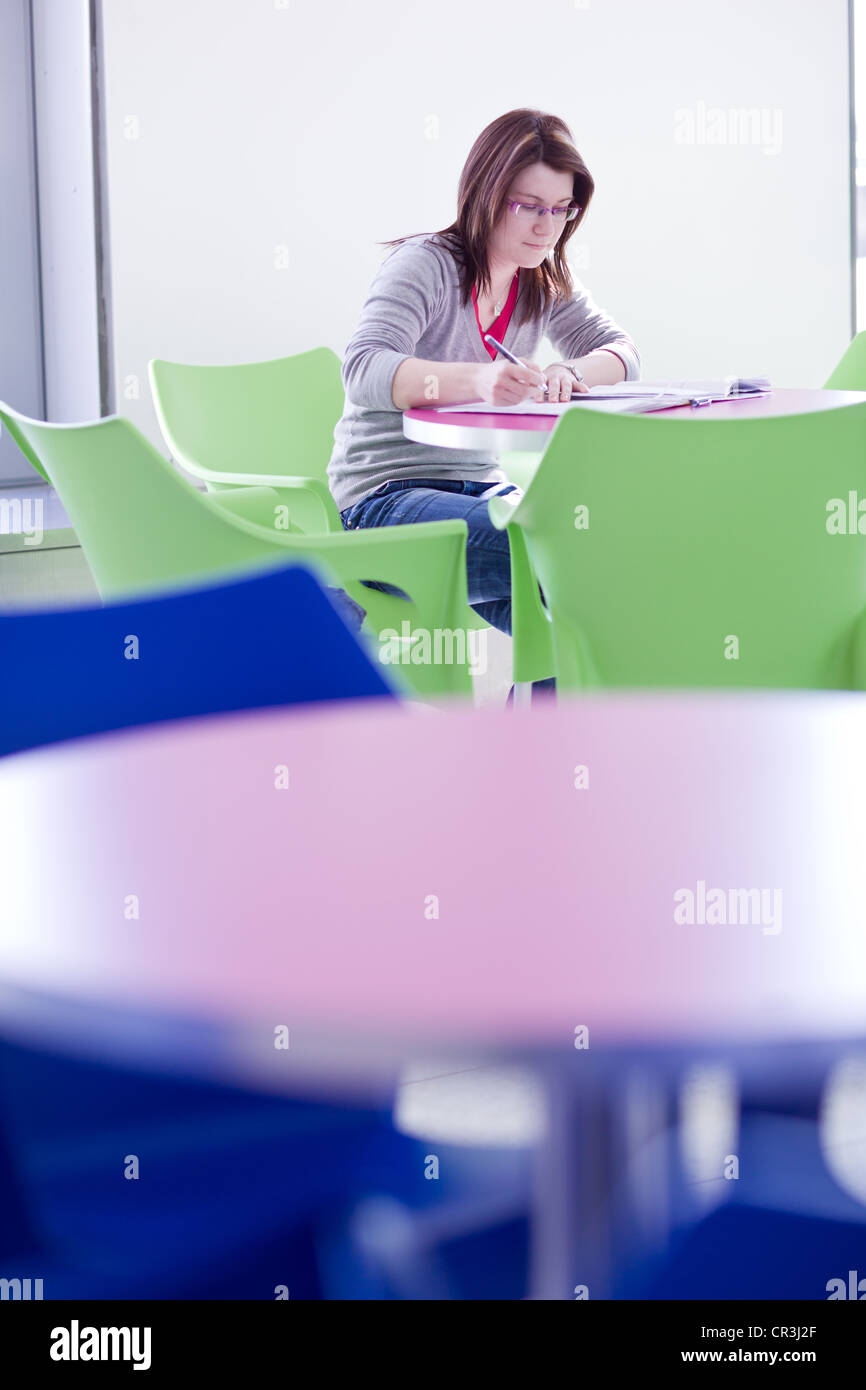 female college student doing homework/assignment on campus/at scchool ...