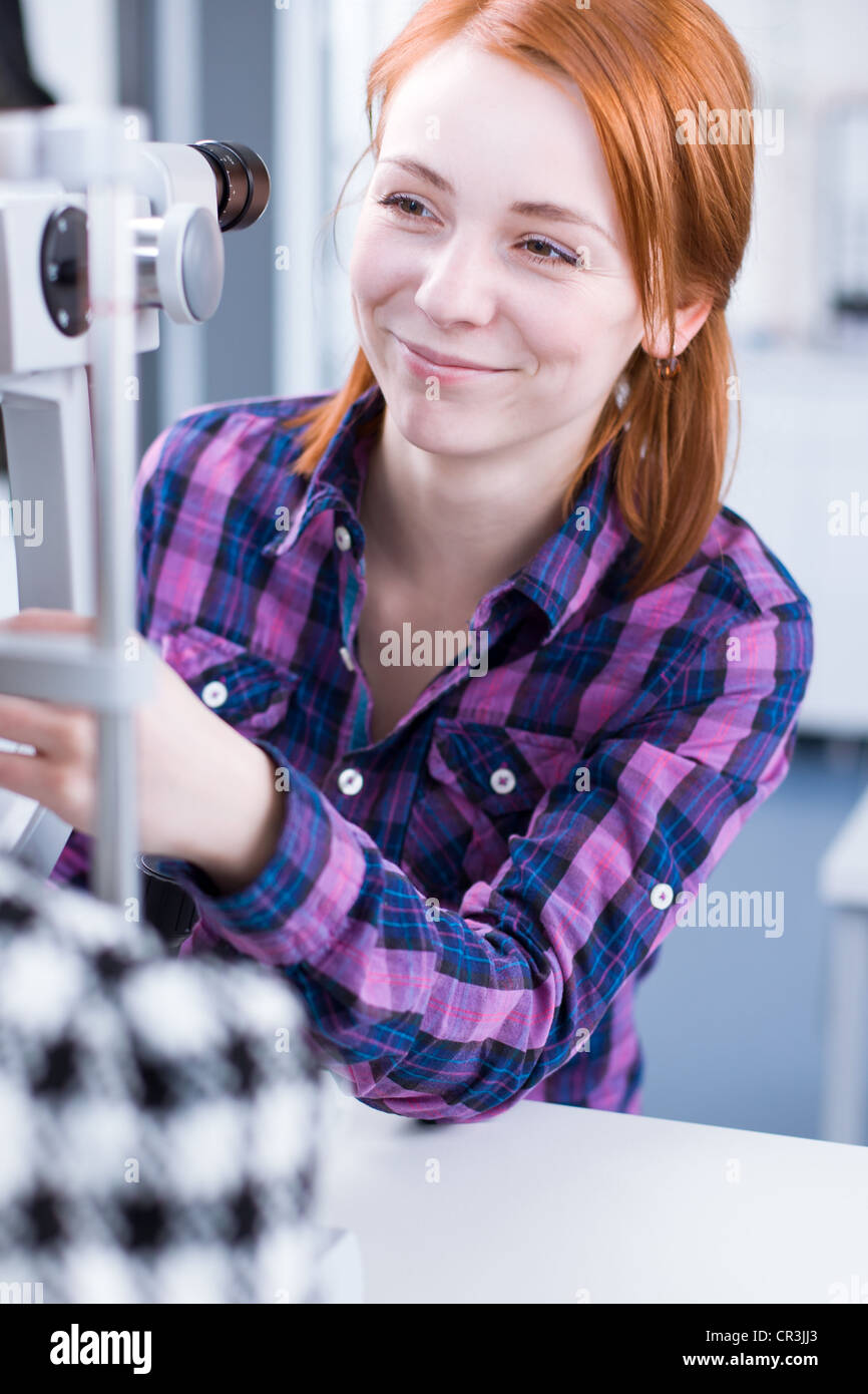 optometry concept - pretty young woman having her eyes examined by an ...