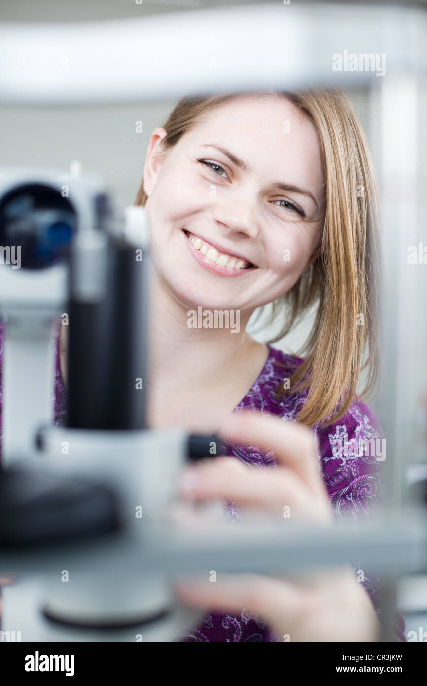 optometry concept - portrait of a young pretty optometrist using slit ...