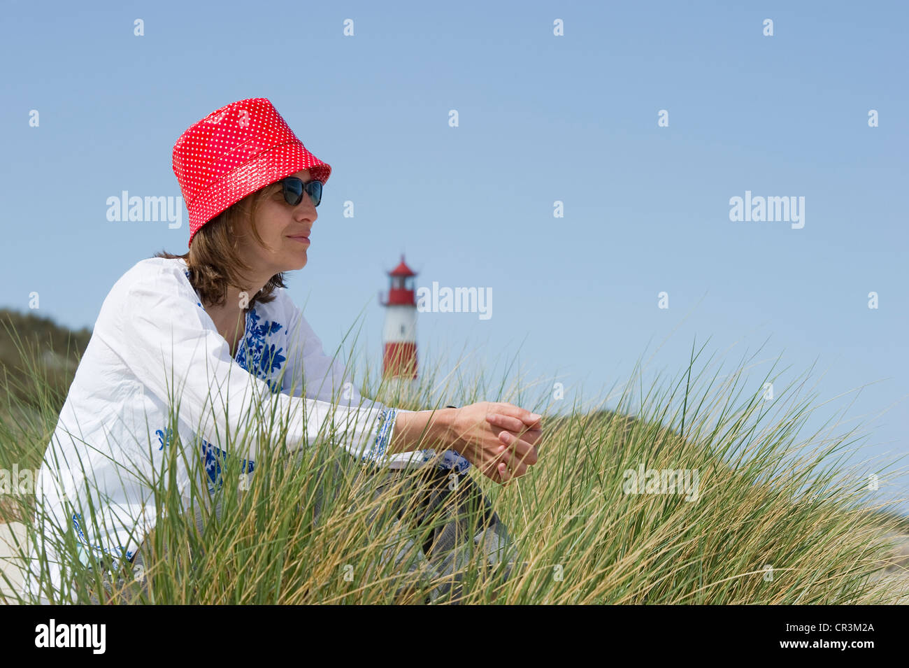 Woman sitting on the beach with lighthouse List-Ost at back, List, Sylt ...