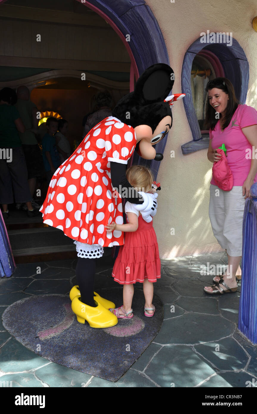 Little girl gets a hug from Minnie Mouse with Mom nearby at Disneyland ...