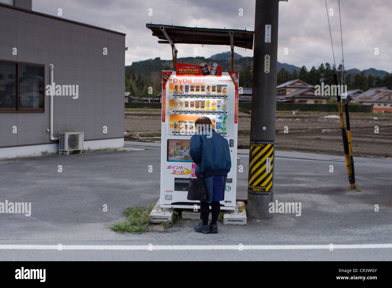 An elderly Japanese woman using a street vending machine in rural Japan ...
