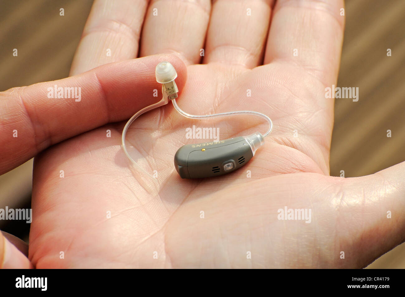 Modern small hearing aid in the palm of a woman, hardness of hearing ...