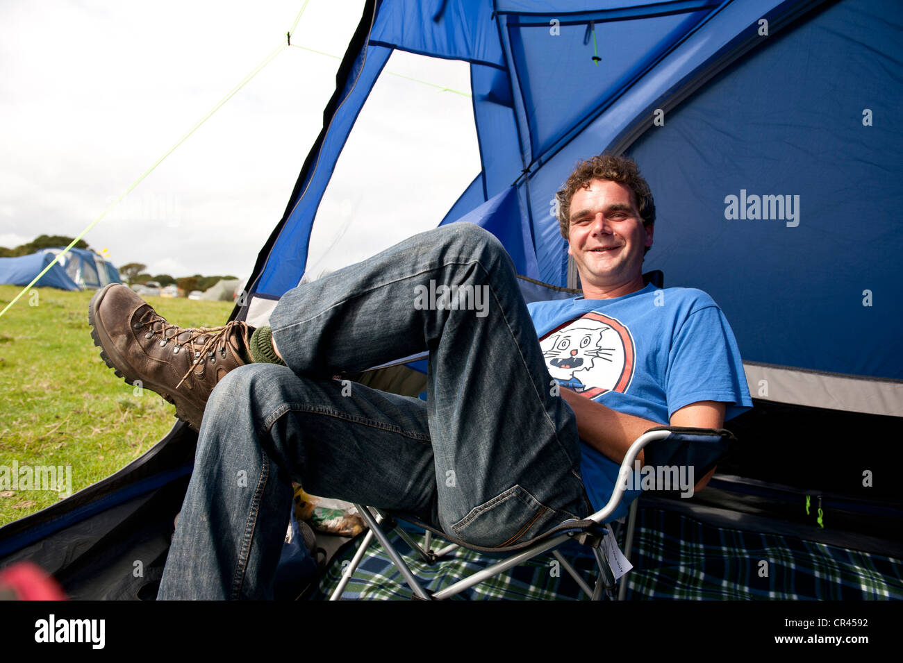 Happy smiling man sitting in tent in a field Stock Photo - Alamy