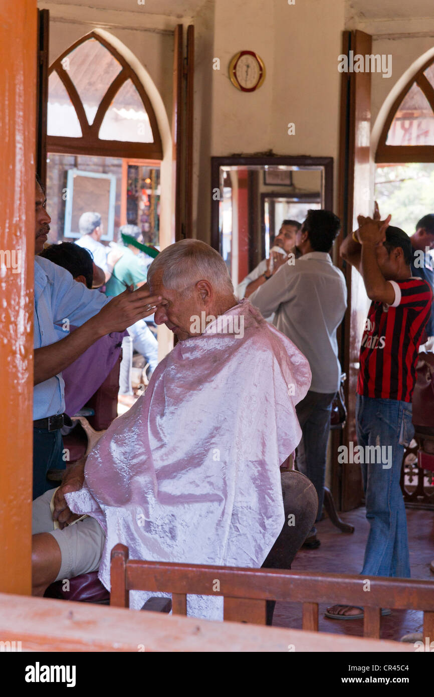 A man in an Indian barbers getting his hair cut Stock Photo - Alamy