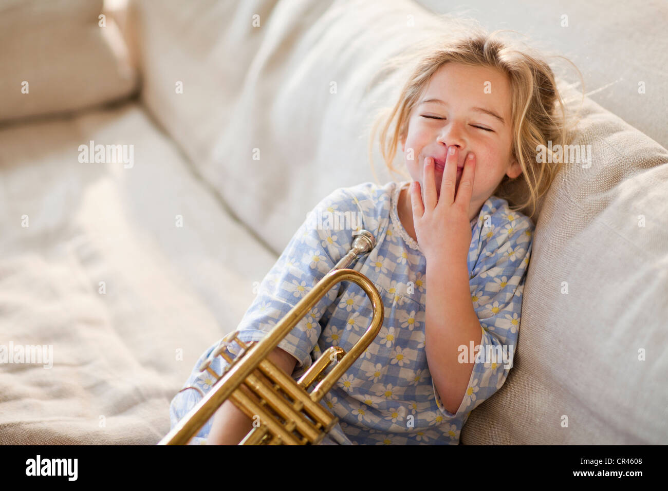 Caucasian girl sitting on sofa with trumpet Stock Photo - Alamy