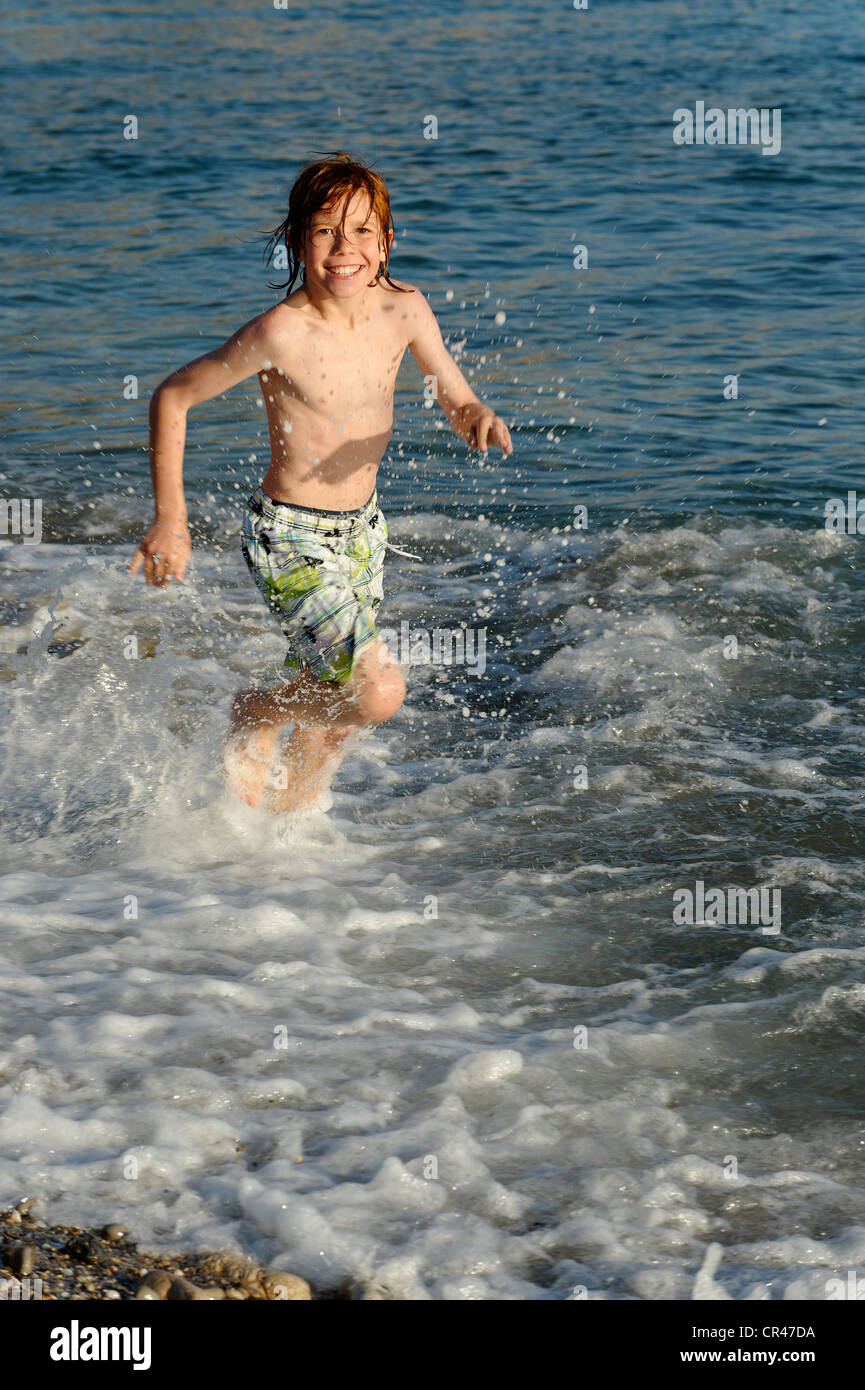 Boy running in the water on a beach by the sea Stock Photo - Alamy