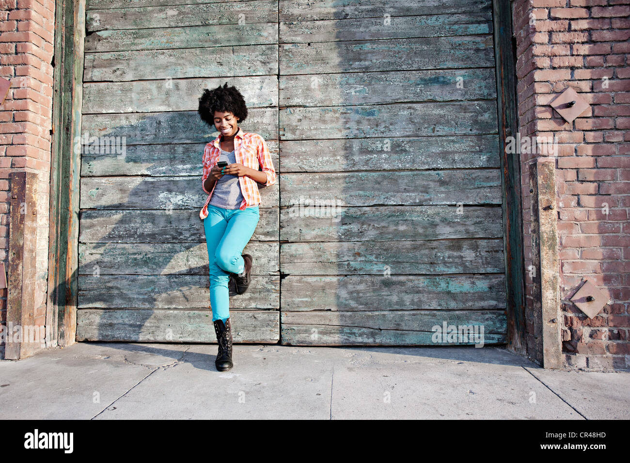 Black woman leaning on wall text messaging Stock Photo - Alamy