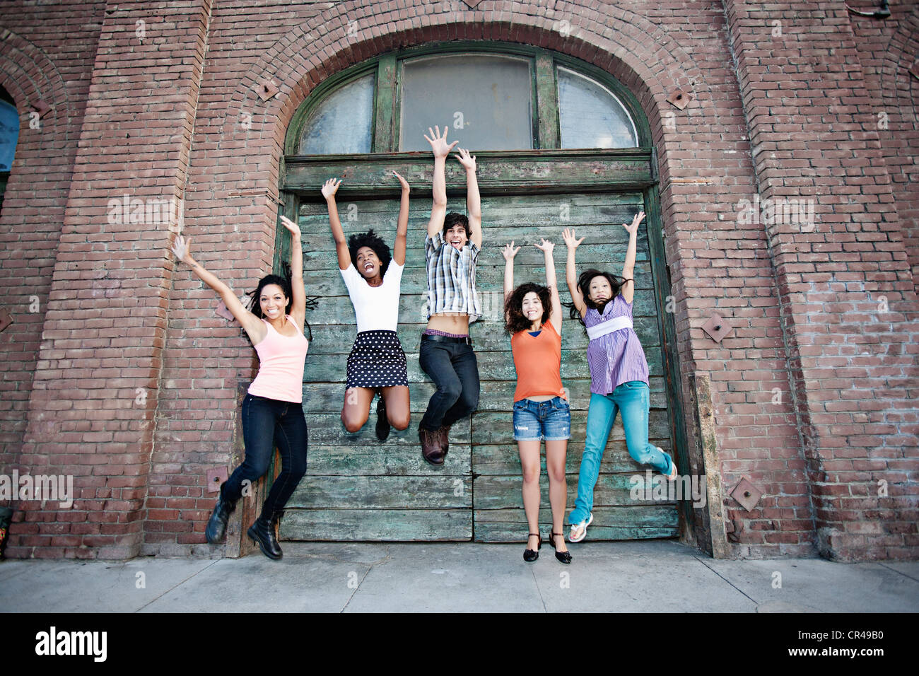 Friends jumping on urban sidewalk Stock Photo - Alamy