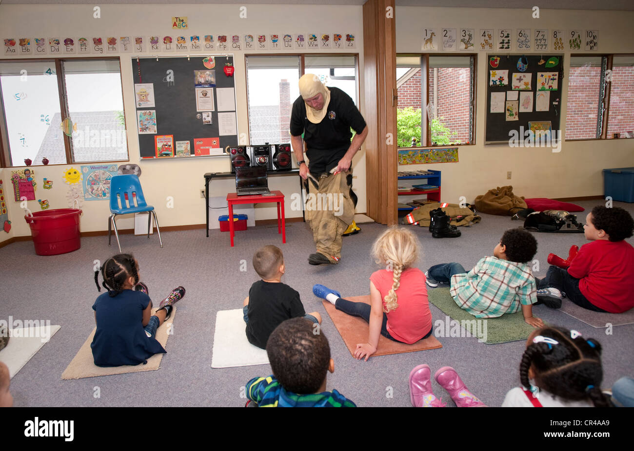 Fireman getting dressed in front of preschool children Stock Photo - Alamy