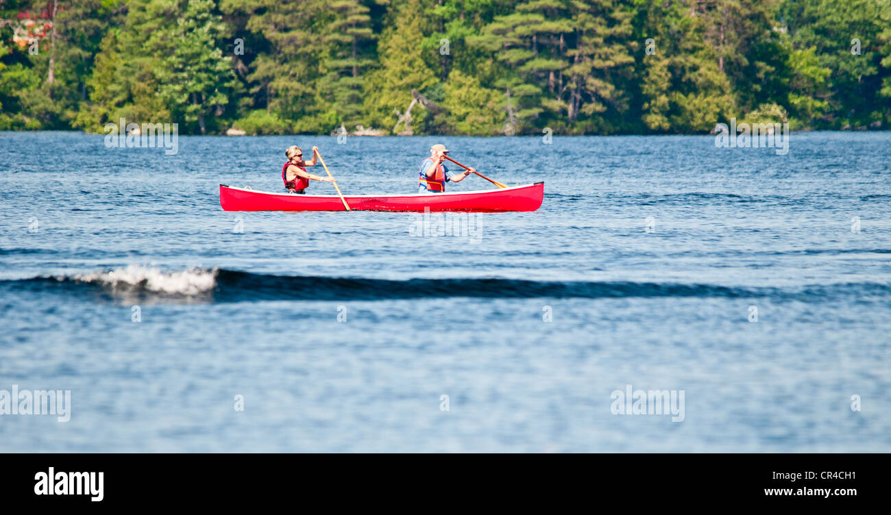 Two adults paddling a red canoe Stock Photo - Alamy