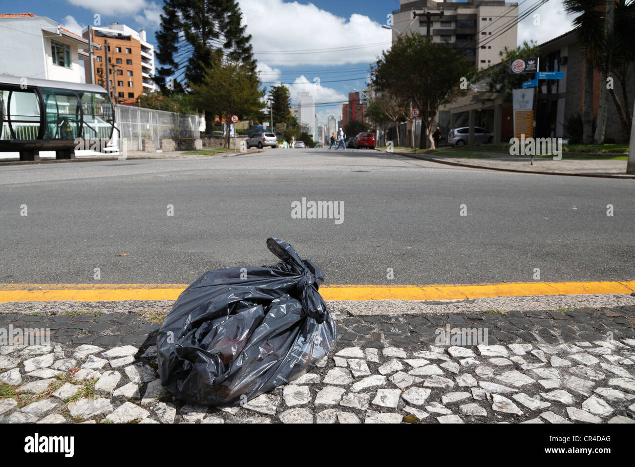 Garbage bag waiting by the roadside of a major city to be picked up ...