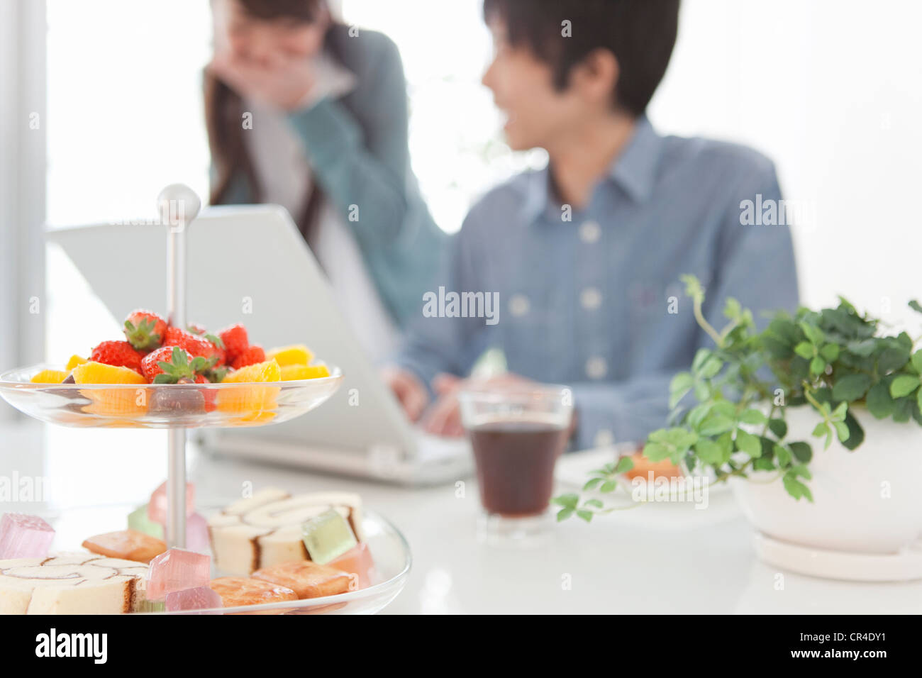 Dining Table, Couple Using Laptop In Background Stock Photo - Alamy