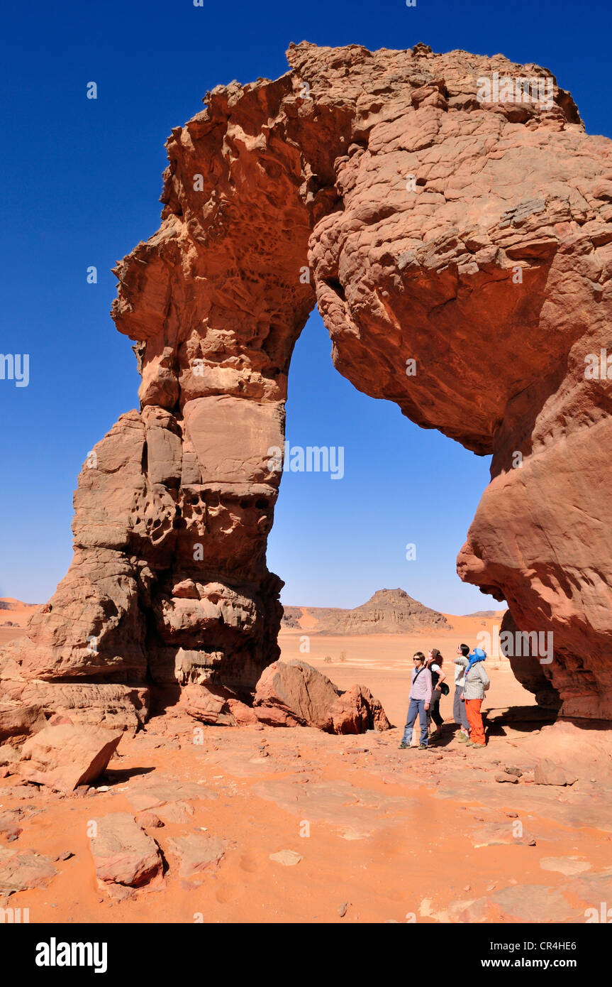 Tourists below the rock arch or natural bridge of In Tehak, Acacus ...