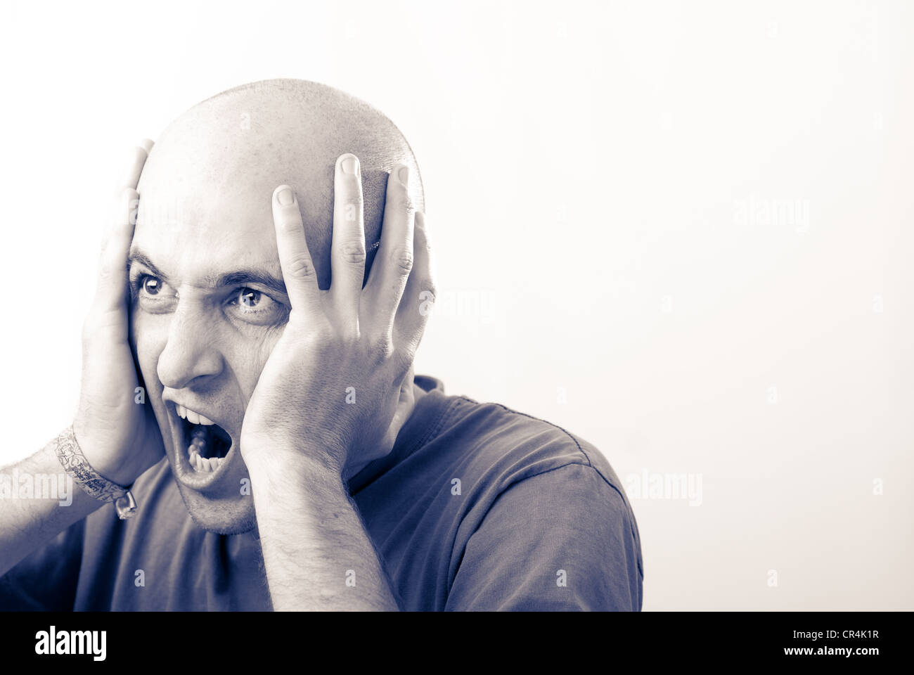 Man holding head with furious mad crazy expression Stock Photo - Alamy