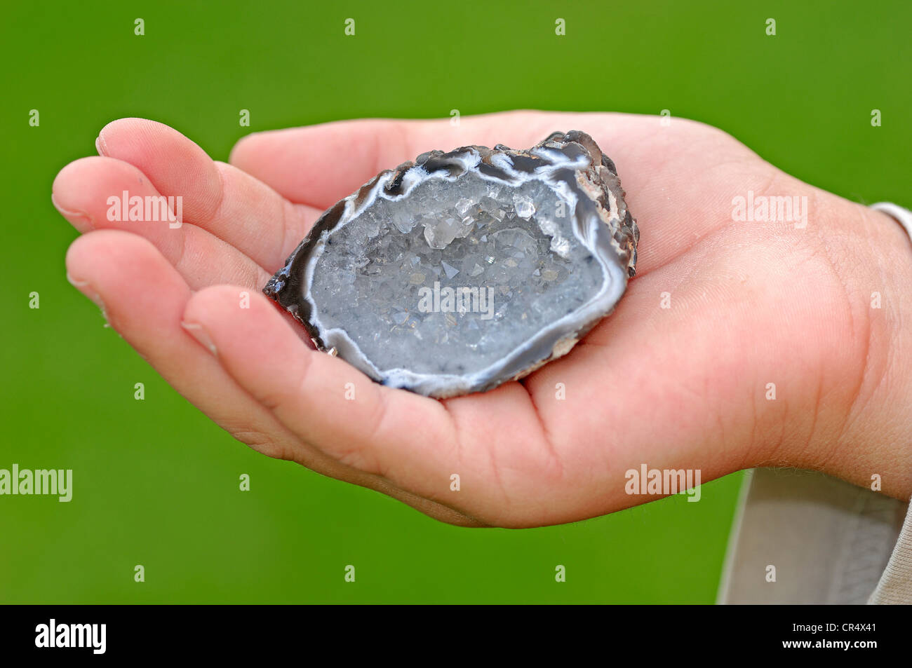 Crystalline quartz in a geode held in a hand, charmstone, precious ...