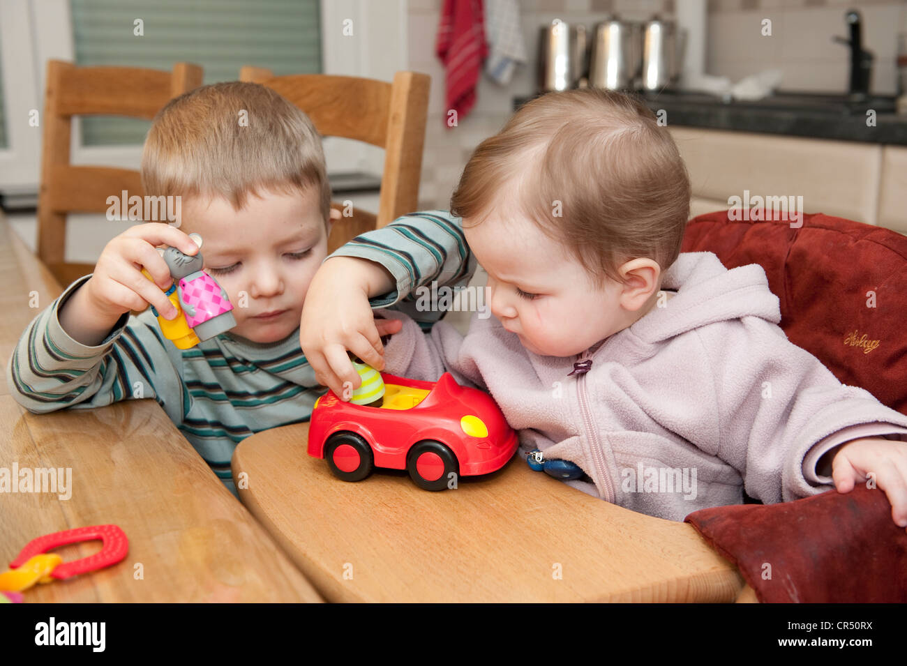 Two children, 3 and 1 years, playing together with a toy car Stock ...
