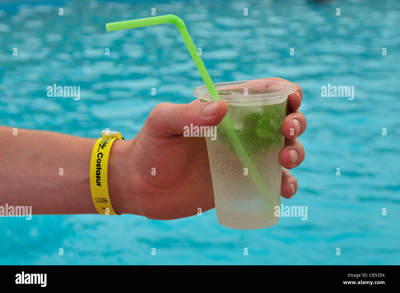 All-inclusive wristband and a mojito cocktail in the hand of a tourist ...