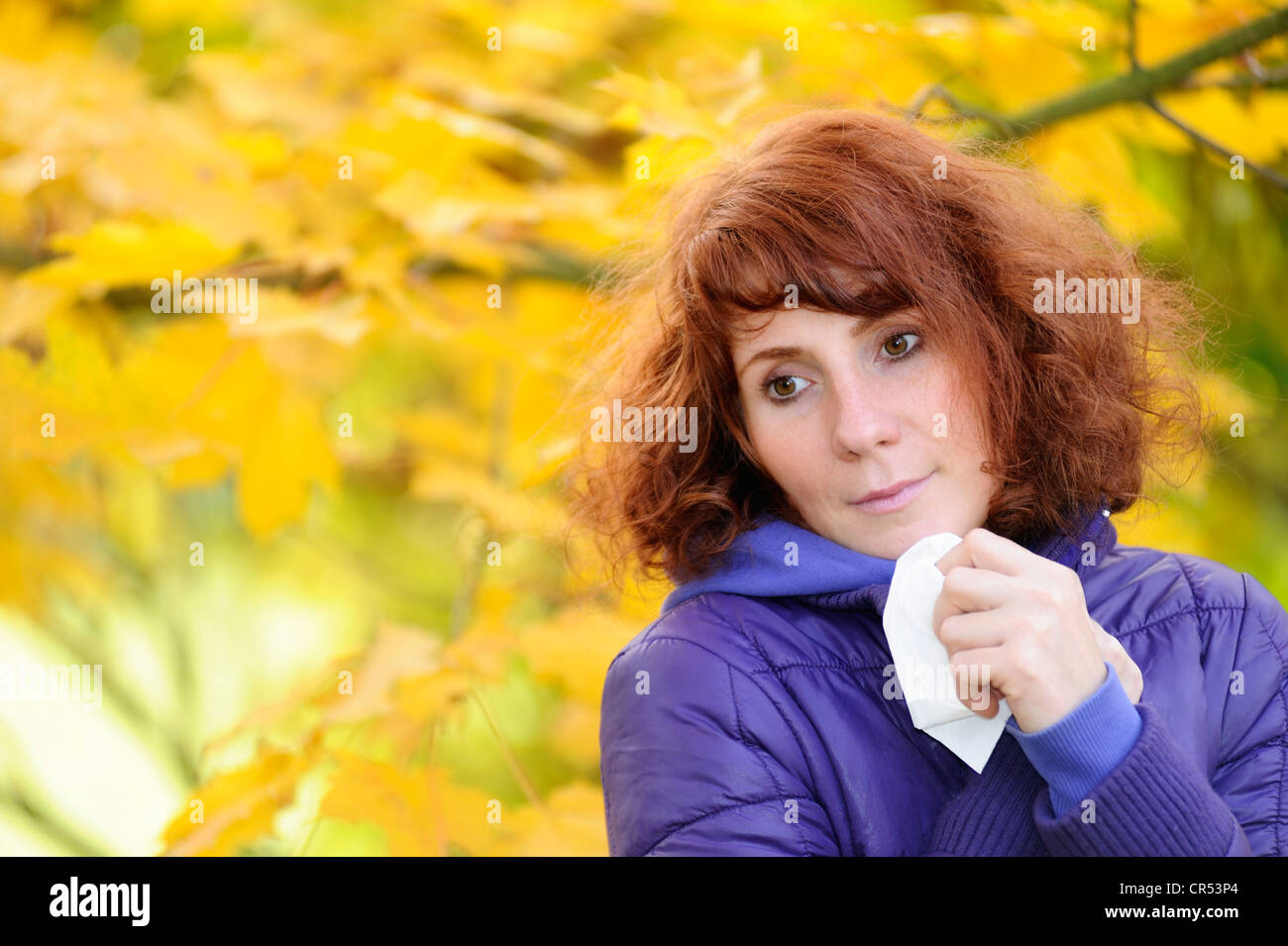 Woman with a cold holding a handkerchief in autumnal surroundings Stock ...