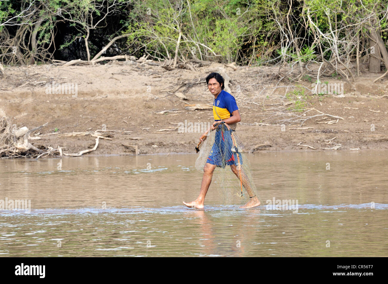 Young man fishing with a net in the Pilcomayo River, indigenous ...