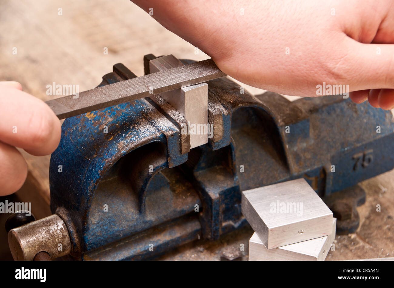 Grinding a block of metal with a file Stock Photo - Alamy