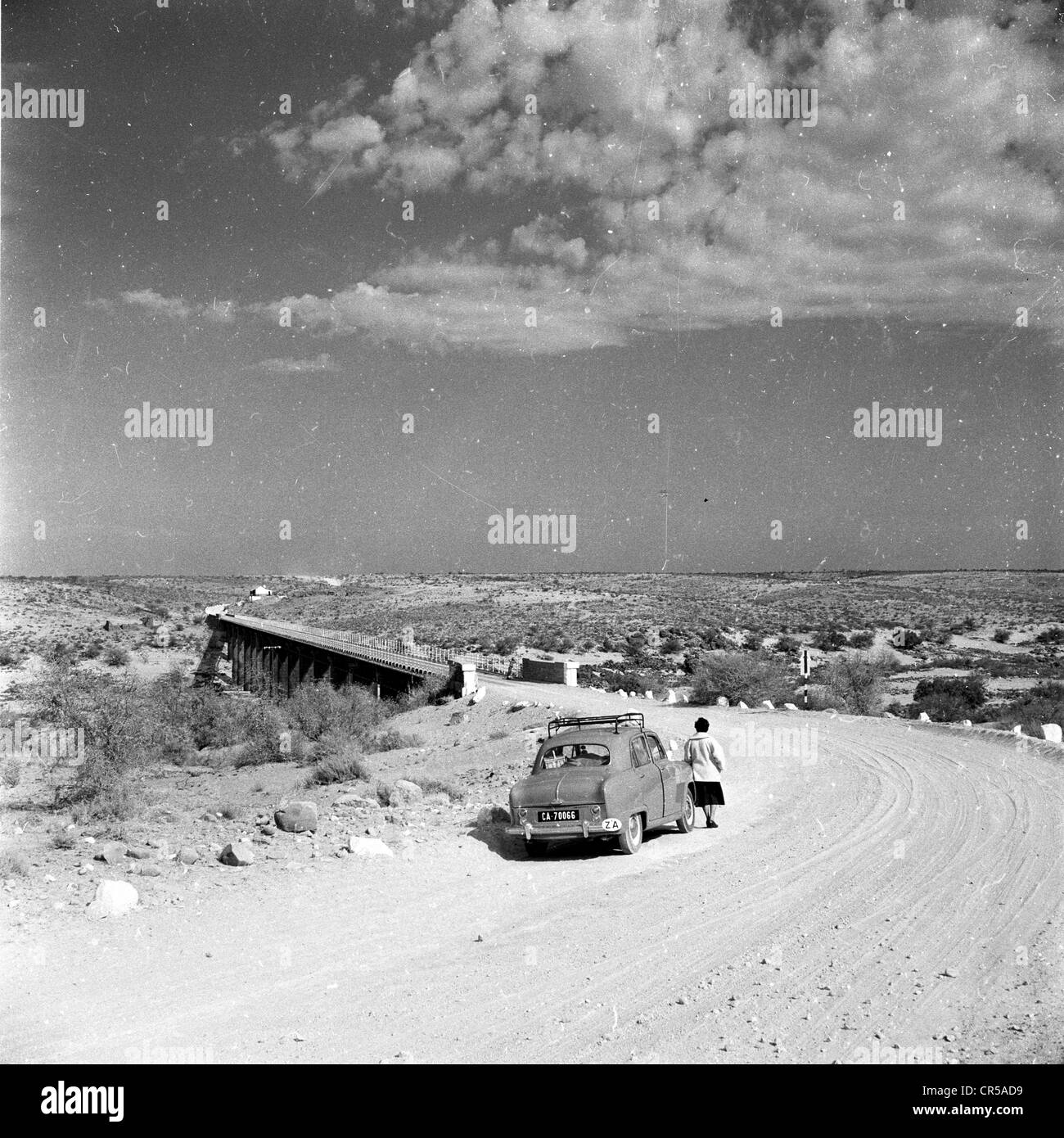 South Africa,1950s. Female tourist stops her car on a dusty, gravel ...