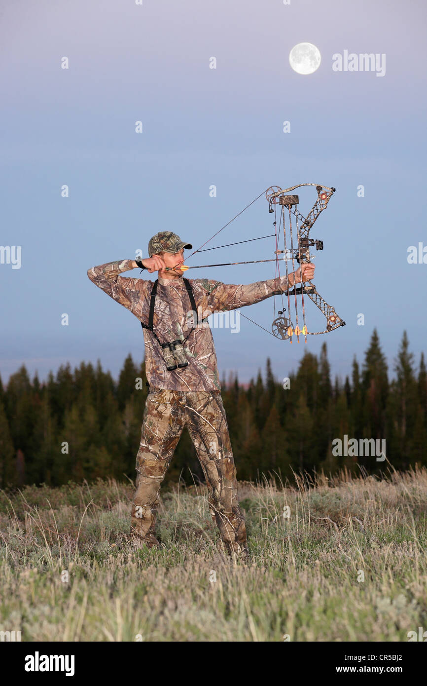 bow hunter drawing bow back in evening with moon Stock Photo - Alamy