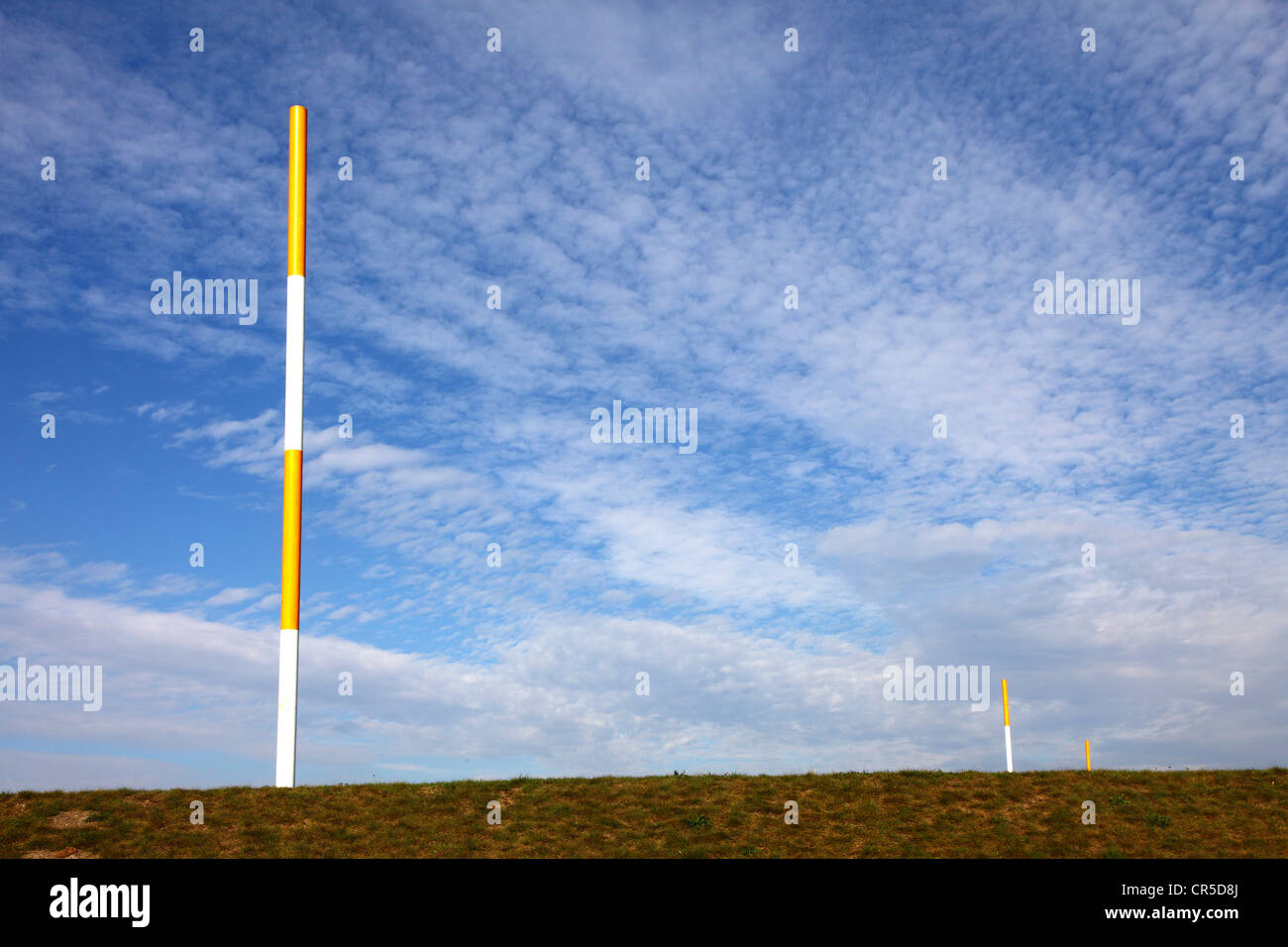 A large, green grass meadow, with orange and white painted rods under a ...