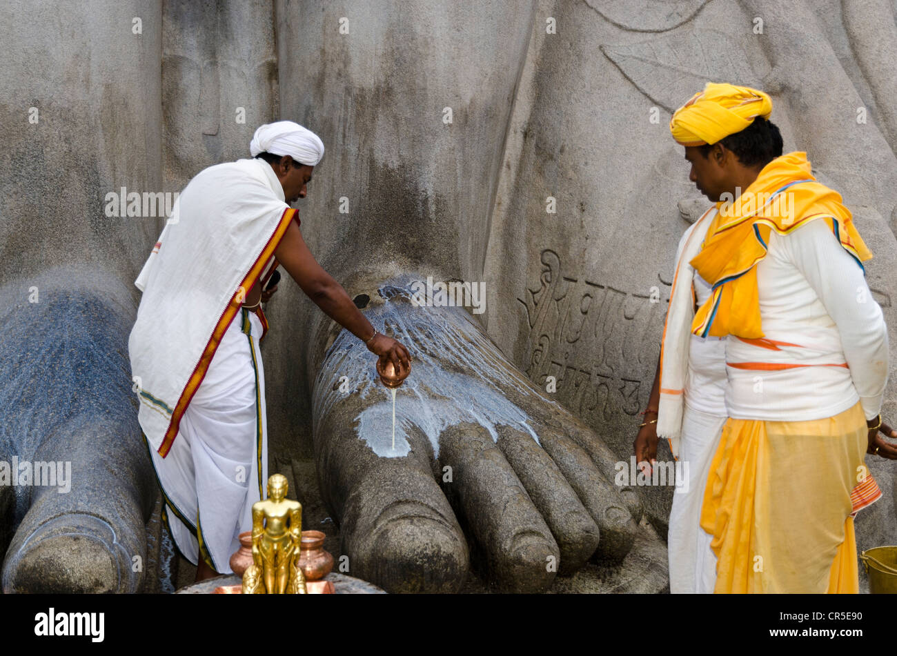 Two local priests are pouring milk over the feet of the statue of Lord ...