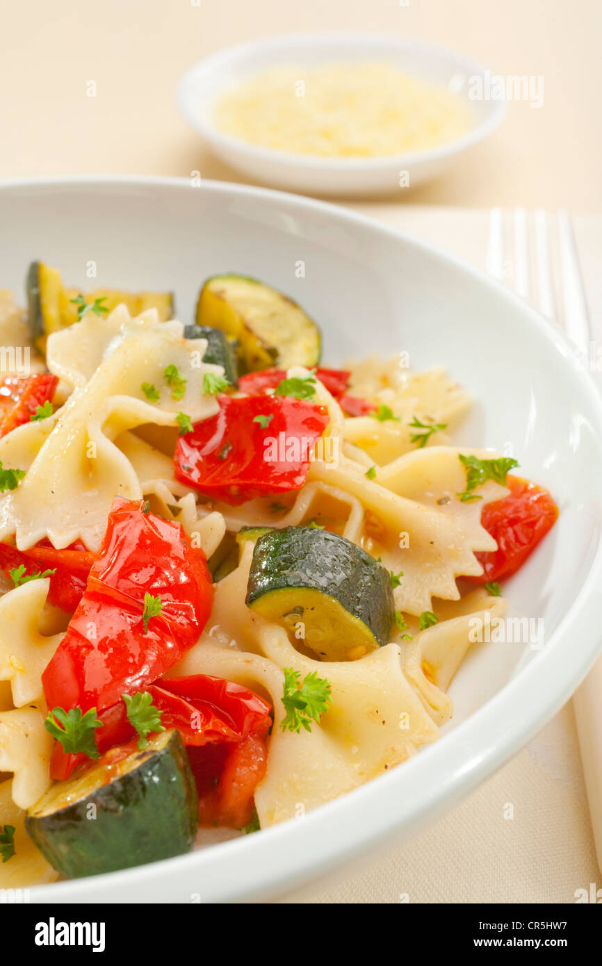 A bowl of pasta bows or farfalle with roast courgettes or zucchini, red ...