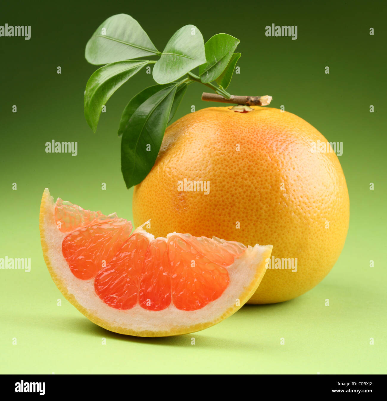 grapefruit with leaves on a green background Stock Photo - Alamy
