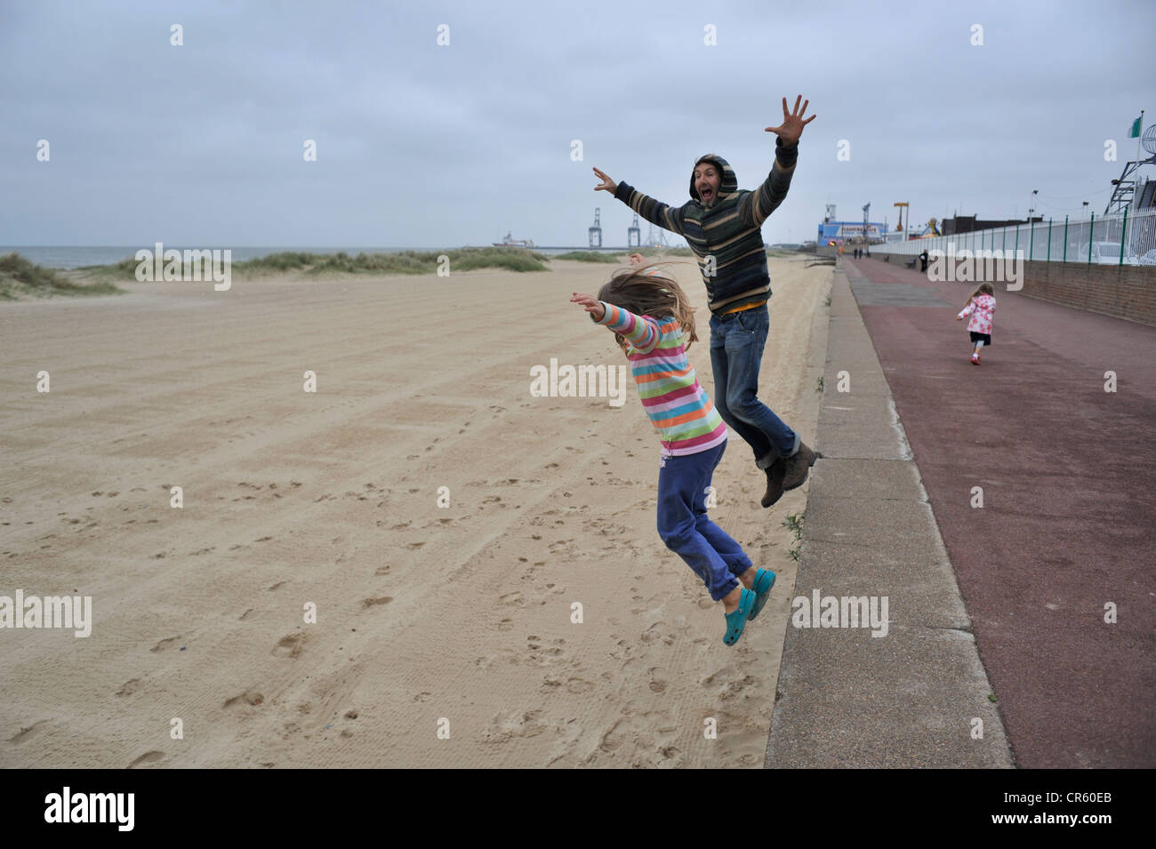 Having fun jumping down into the sand at Great Yarmouth Stock Photo - Alamy