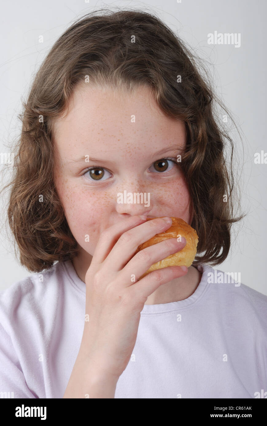 A young girl eating a bun Stock Photo - Alamy